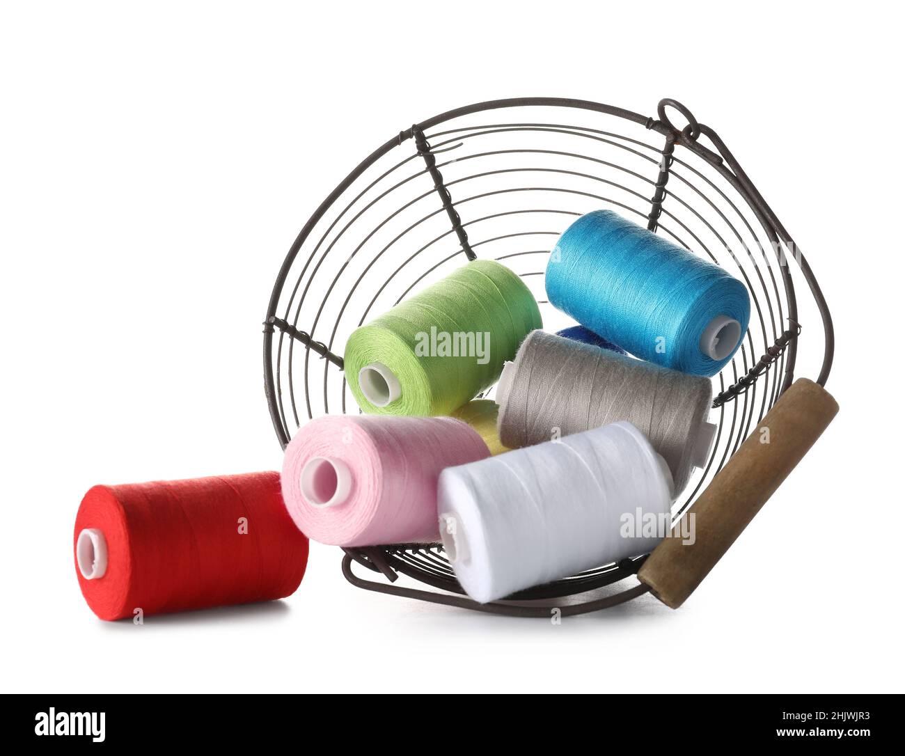 Wire basket with different sewing thread spools on white background ...