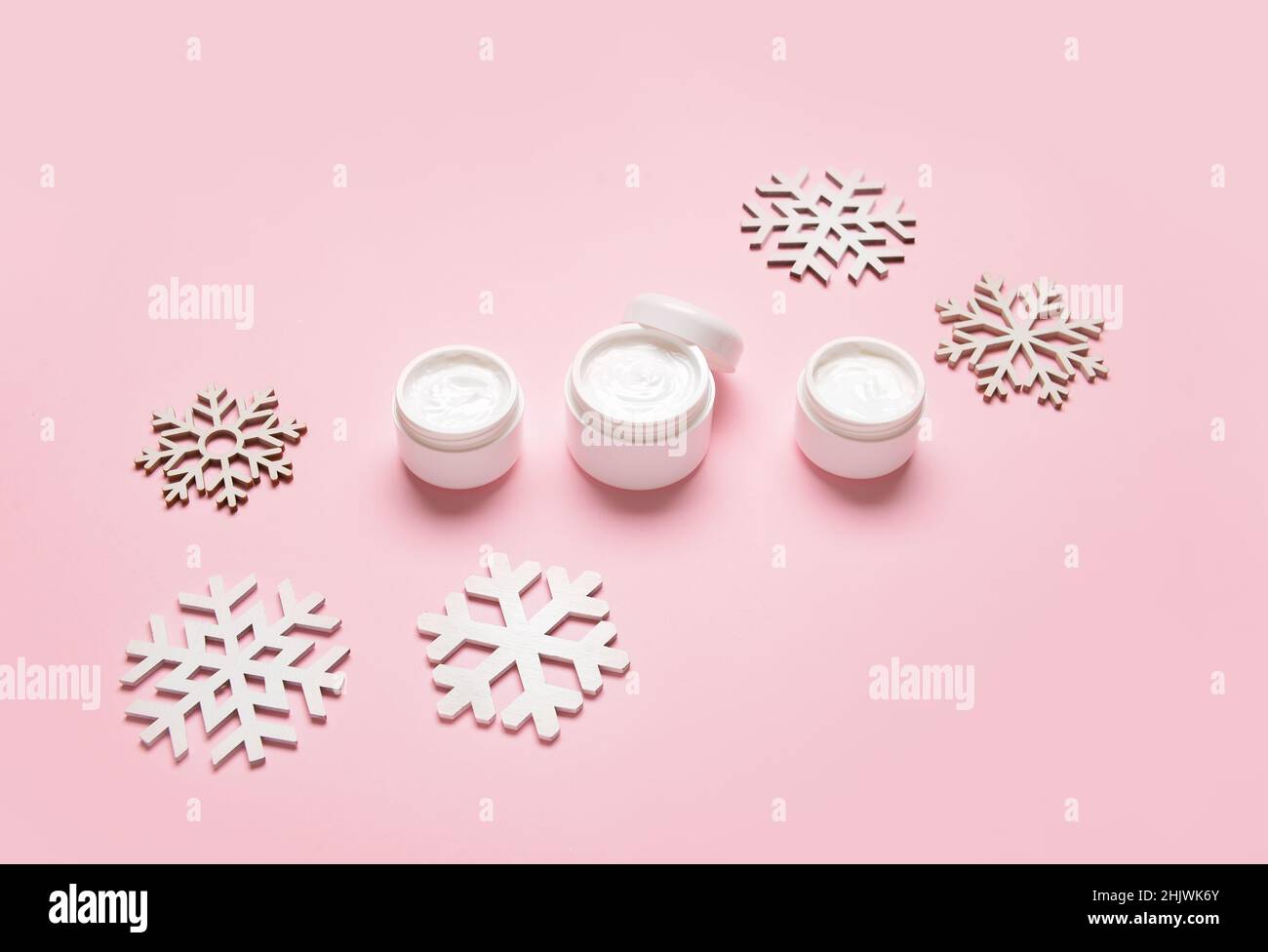 Jars with cream and snowflakes on color background Stock Photo - Alamy