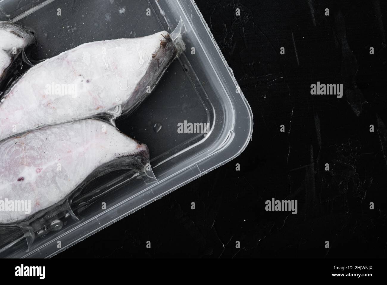 Frozen halibut pack set, on black dark stone table background, top view ...