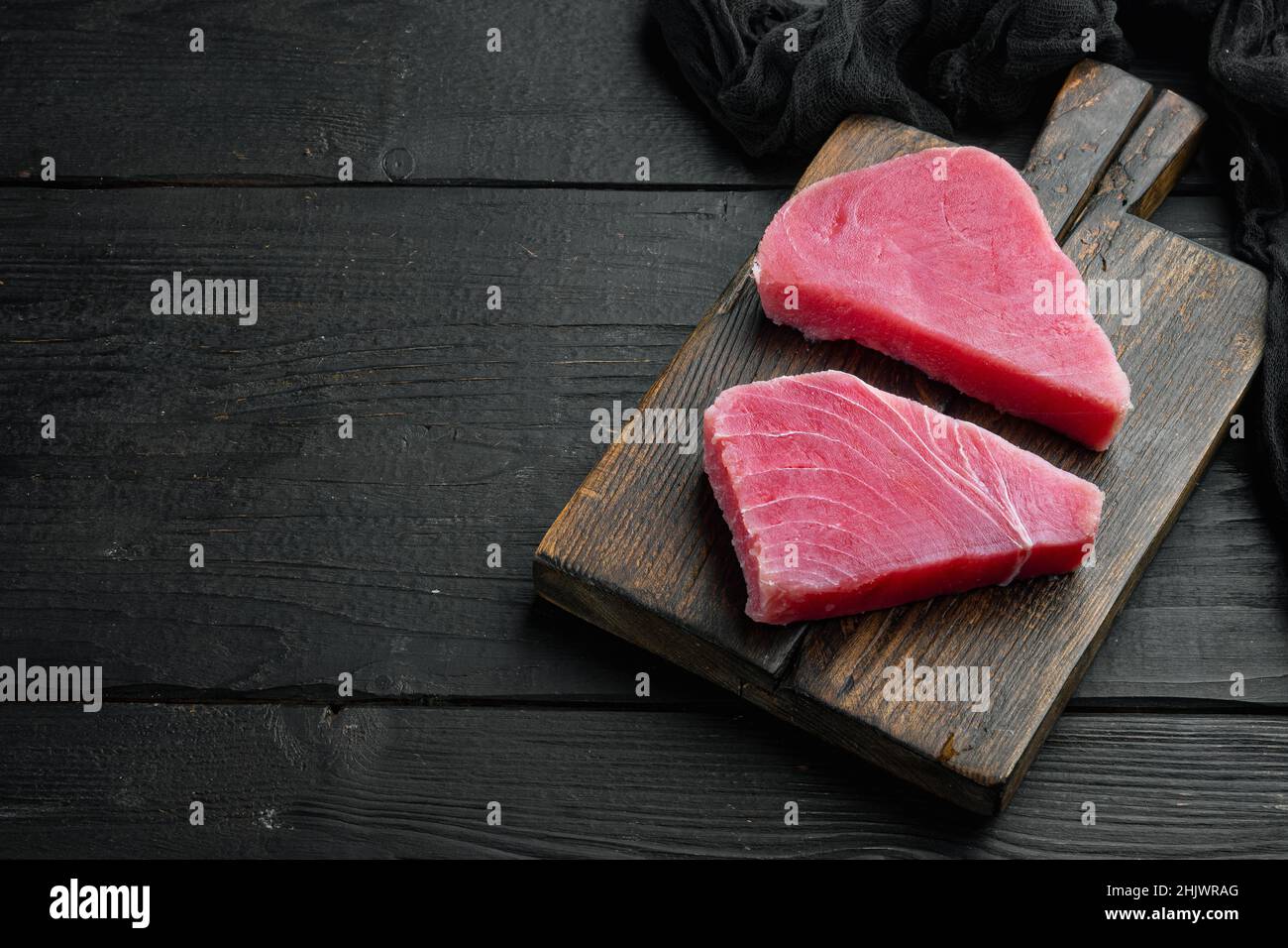 Pieces of raw tuna fish set, on wooden cutting board, on black wooden ...