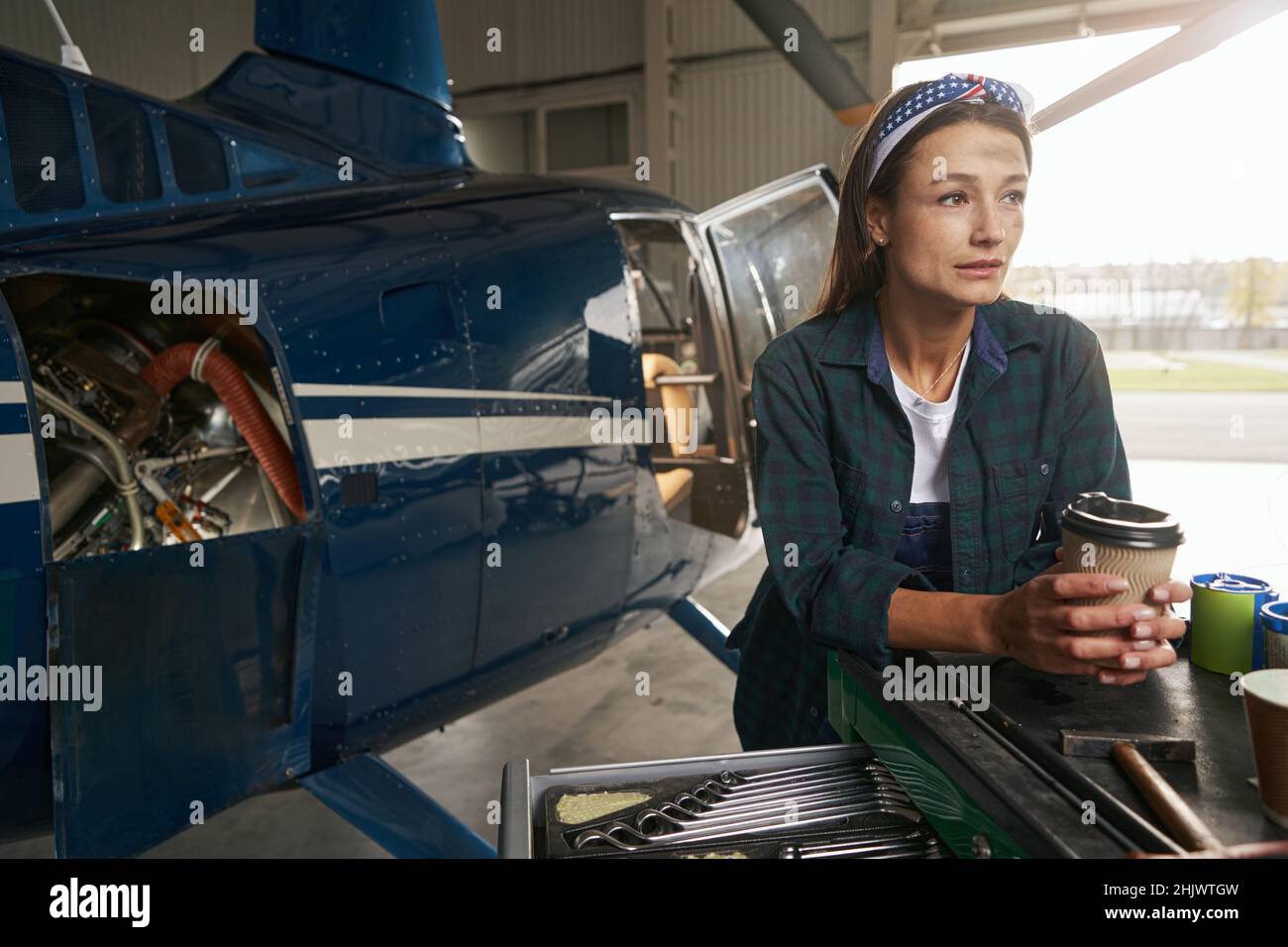Woman engine mechanic standing in front of the private jet airplane in ...