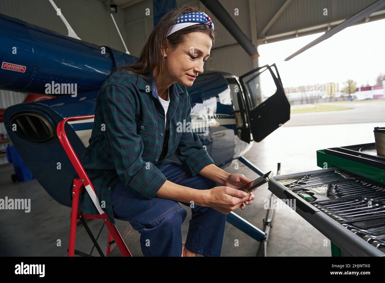 Woman engine mechanic sitting in front of the private jet airplane in ...