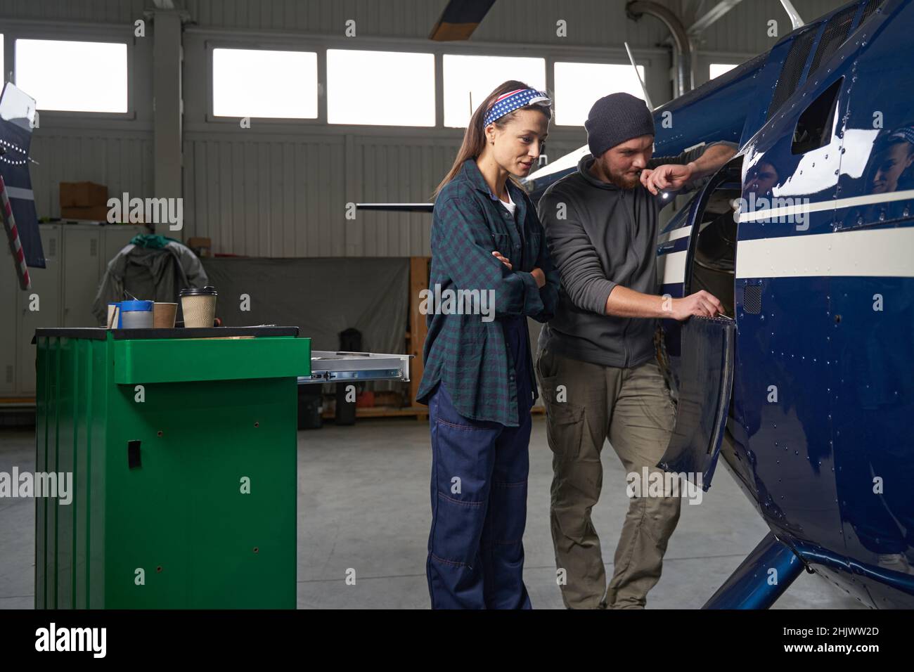 Male with flashlight in hand working with female while inspecting plane ...