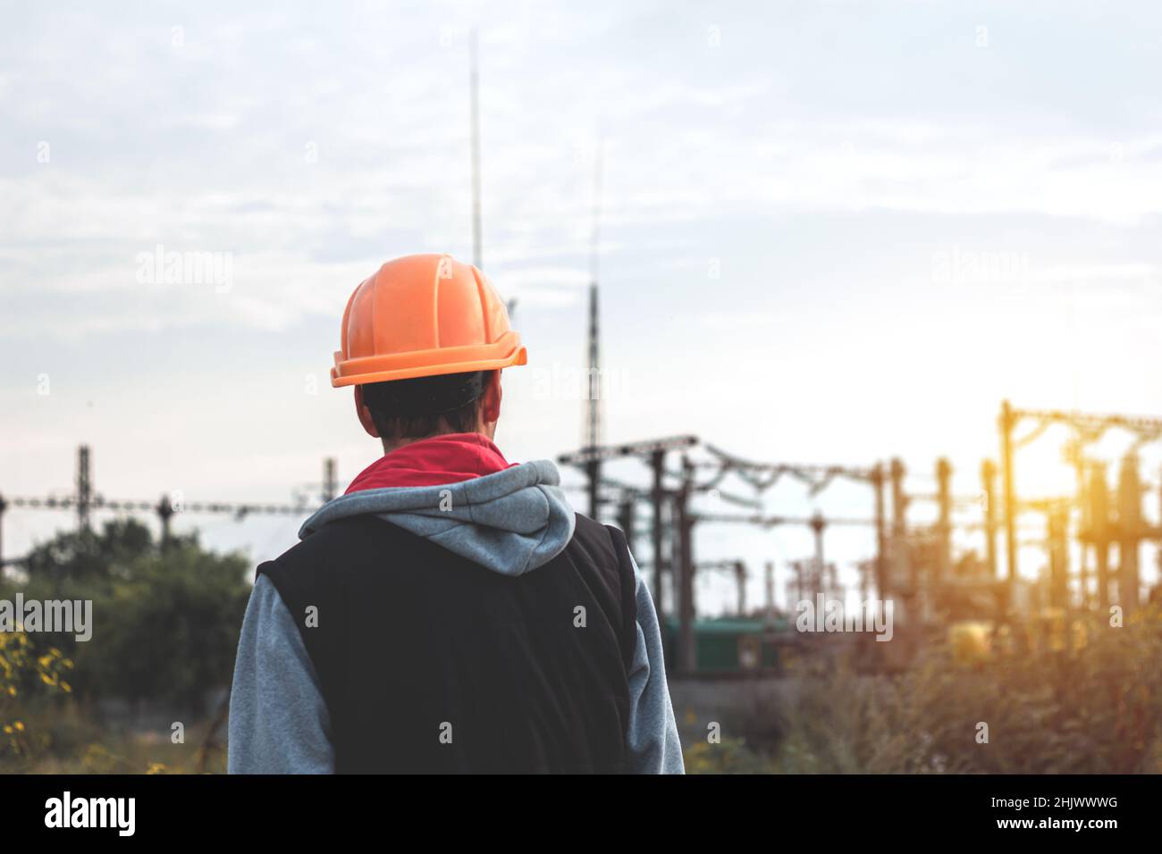 Worker in a helmet against the background of a substation and high ...