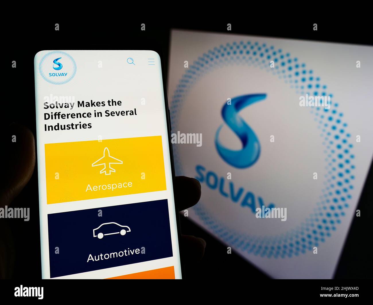 Person holding cellphone with webpage of Belgian chemical company ...