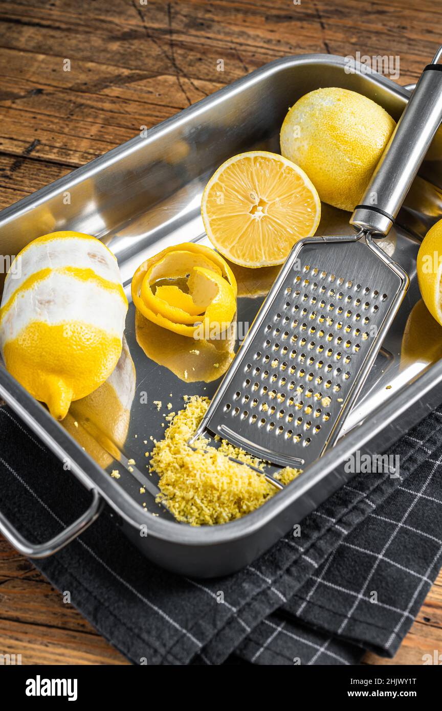 Cooking with Grated Lemon Zest and spiral peel in kitchen tray. Wooden ...