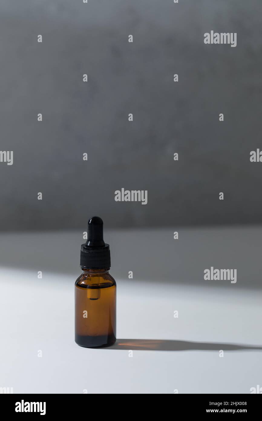 Brown glass dropper with serum for facial skin on a light grey ...