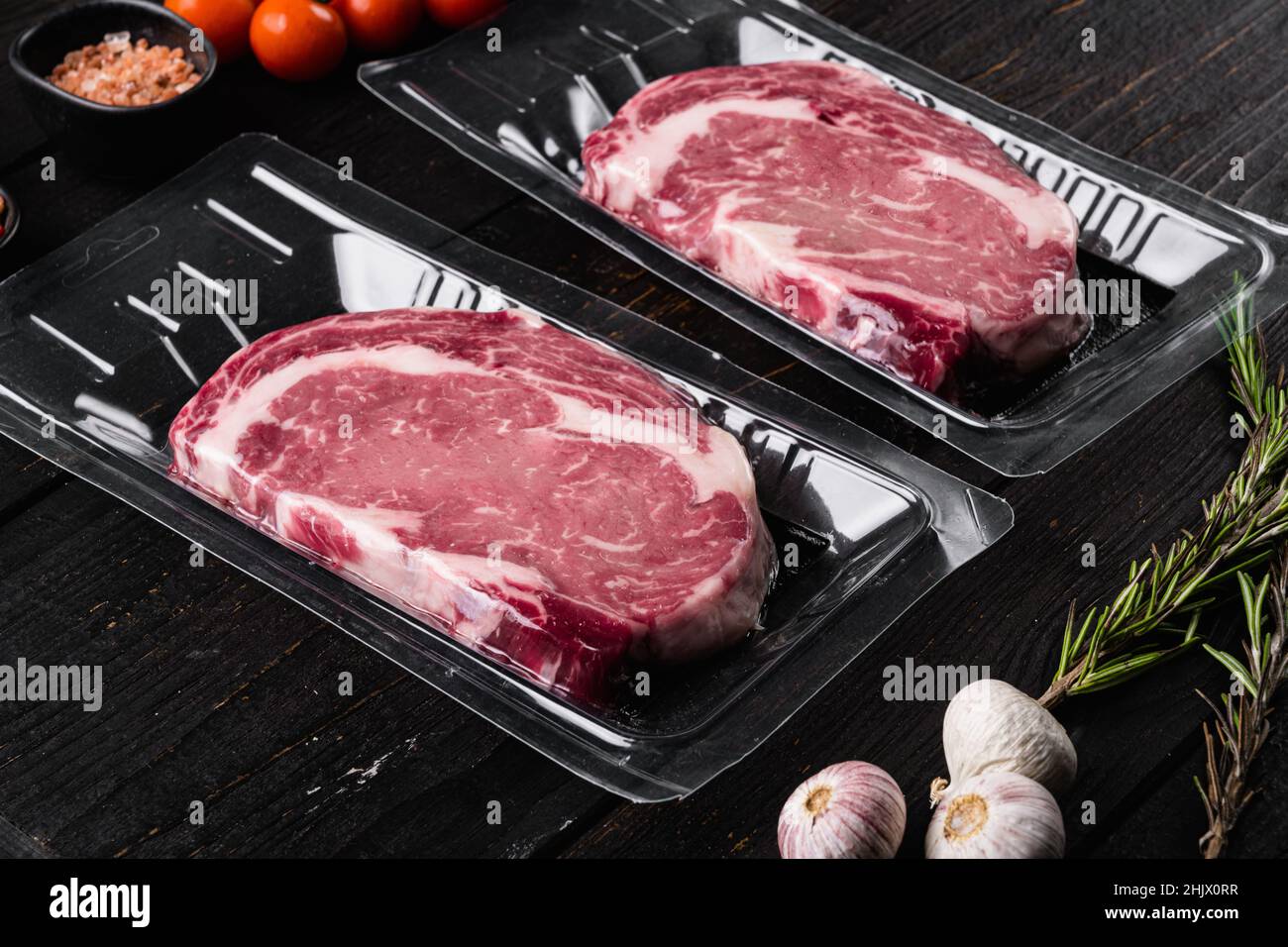 Packing raw beef steak in vacuum set, on black wooden table background ...