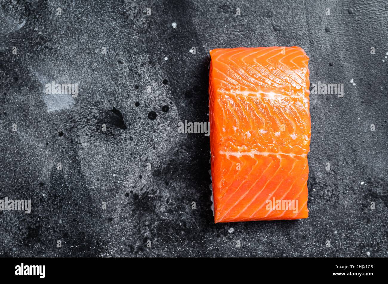 Raw salmon fillet steaks on kitchen table. Black background. Top view ...
