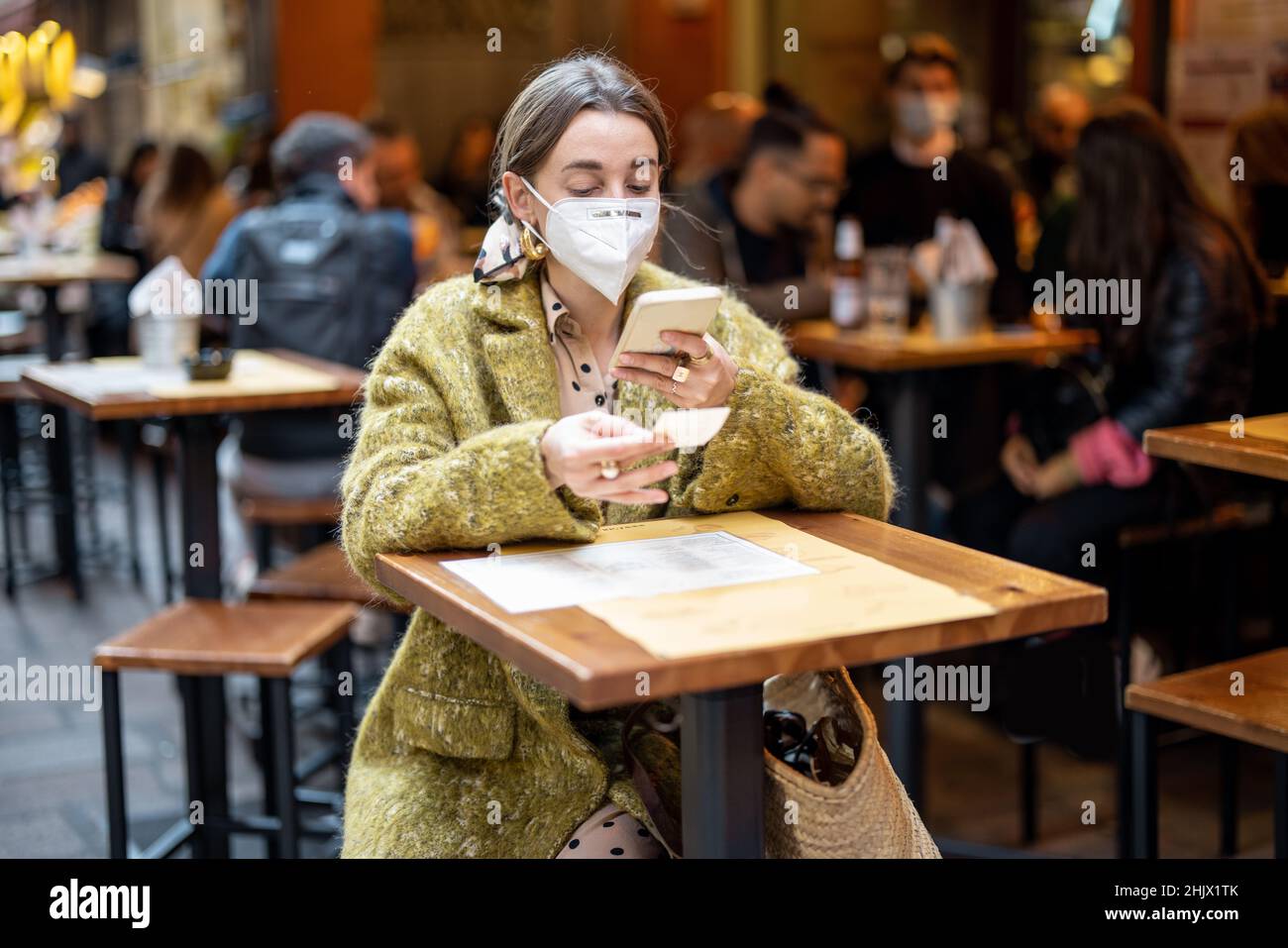Woman in medical mask photographing qr code of restaurant menu outdoors ...
