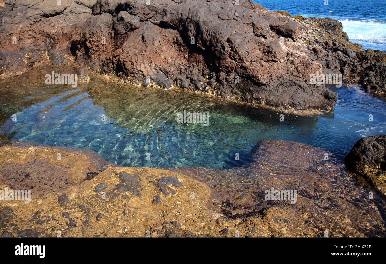 Gran Canaria, calm rock pools under steep cliffs of the north coast are ...