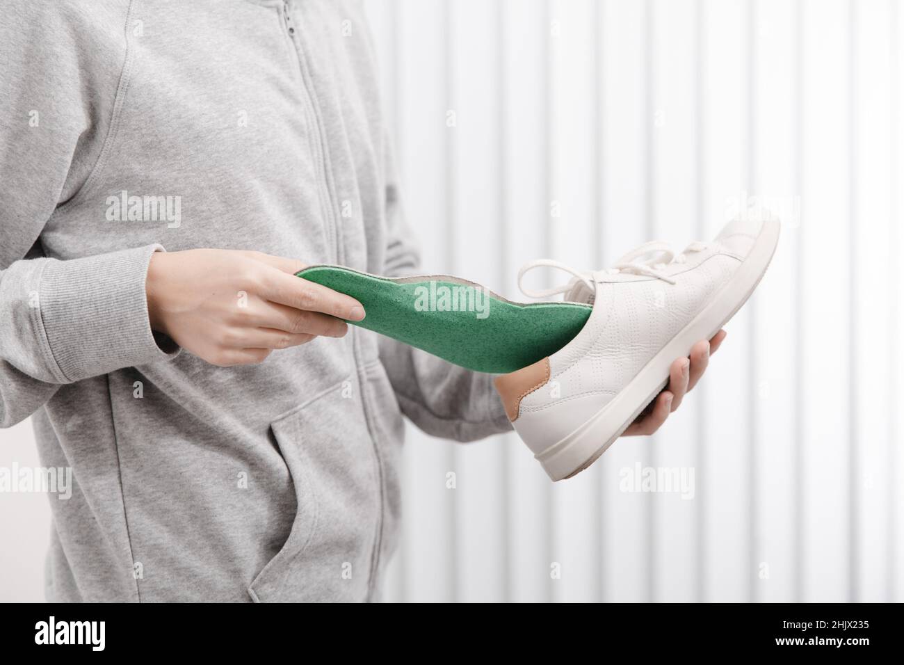 Woman putting orthopedic insole into shoe at home. Sports girl fitting ...