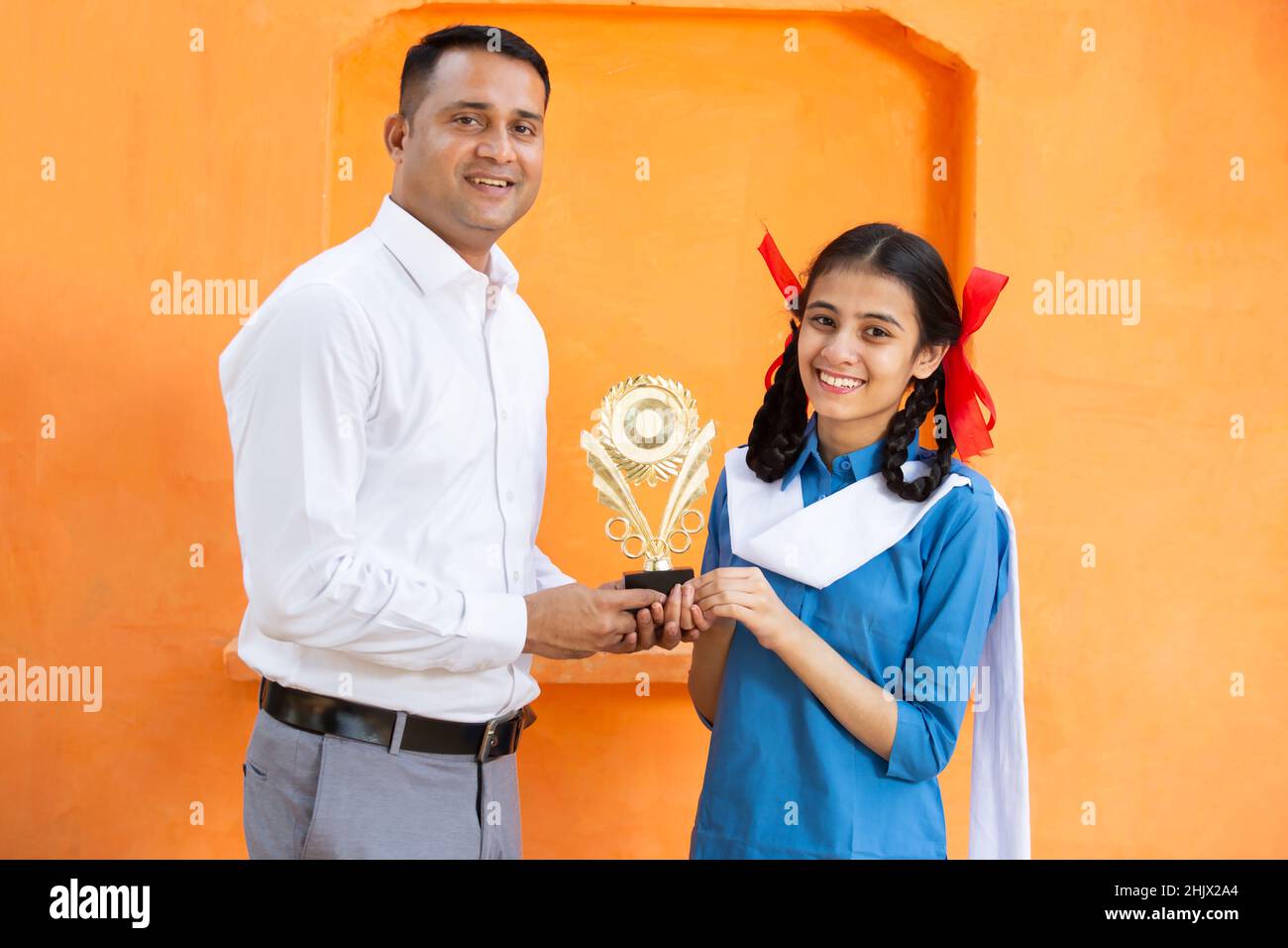 Handsome young Indian man school teacher give victory trophy to girl ...