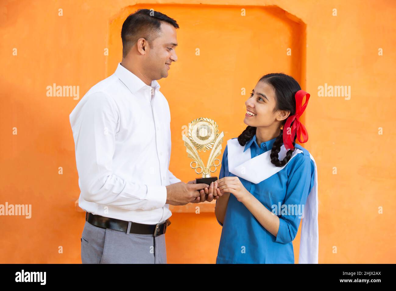 Handsome young Indian man school teacher give victory trophy to girl ...