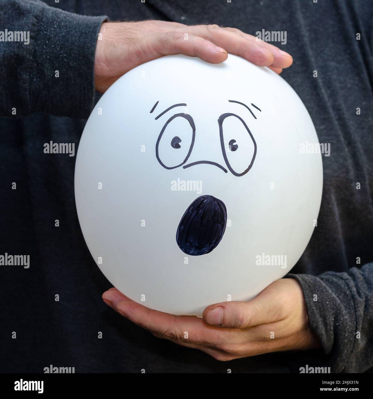 Man holding balloon with face drawn in front of him. White balloon with ...