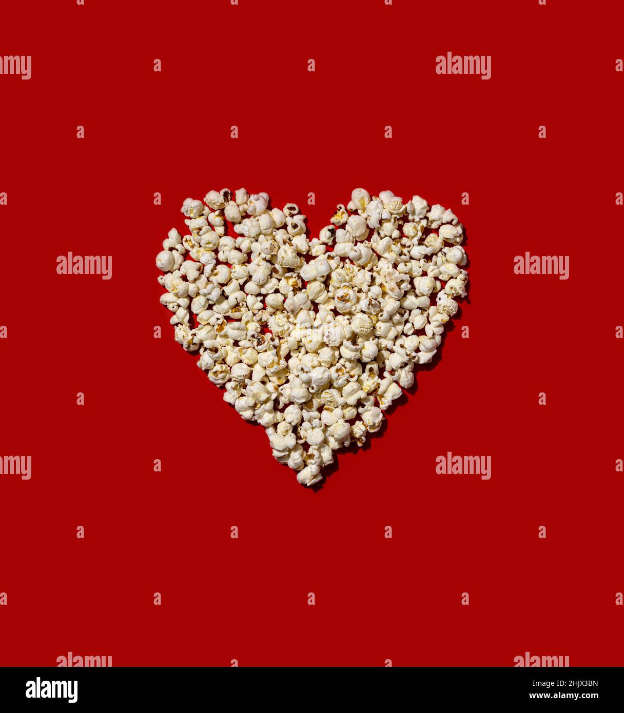 Heart made of popcorn on red background Stock Photo - Alamy
