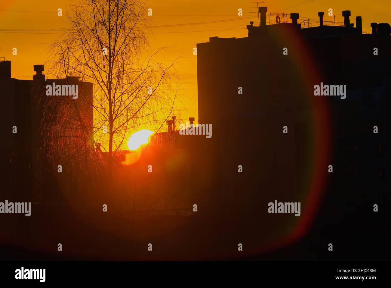 Sunset in city between multi-storey buildings. Silhouette of houses ...