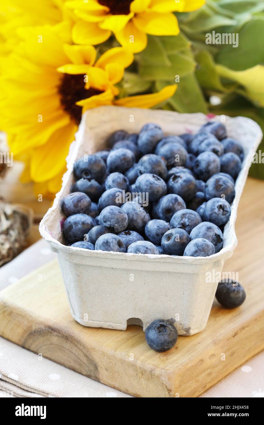 Paper box with blueberries and flowers in the background. Healthy food ...