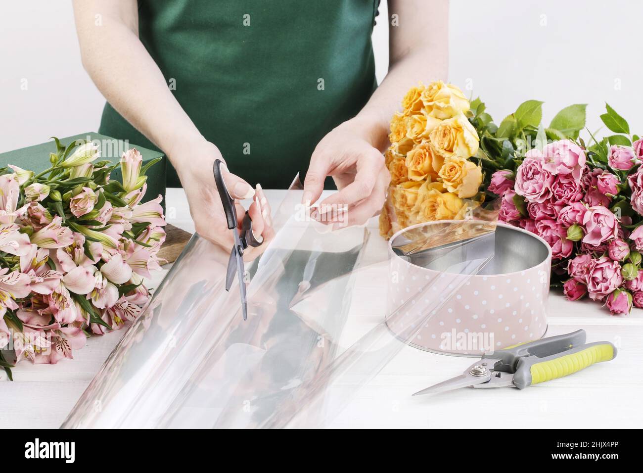 Florist at work: woman shows how to make floral arrangement with roses ...