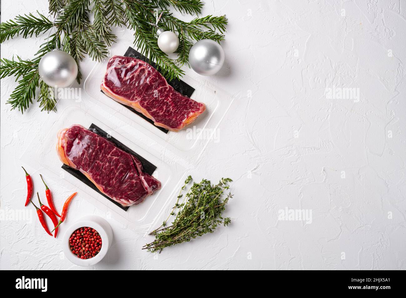 Vacuum packed New-York steak with a Christmas tree set, on white stone ...