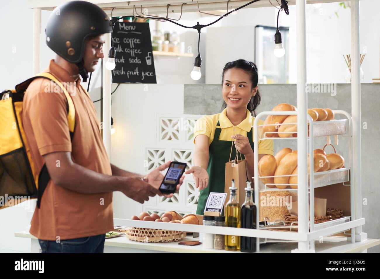 Smiling vendor asking courier to scan QR code with camera on his ...