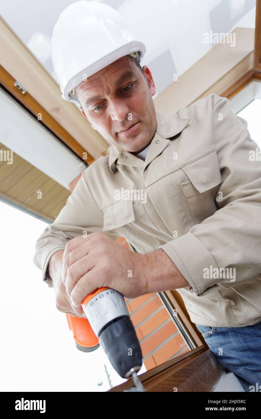 low angle view of mature builder drilling wooden window frame Stock ...