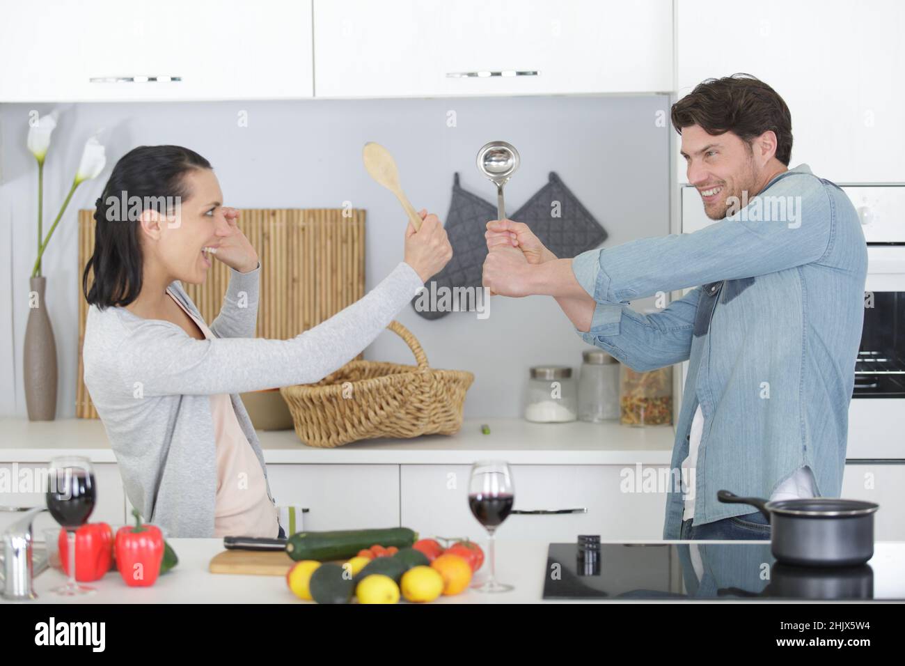 funny couple fight with utensils tools while cooking Stock Photo - Alamy