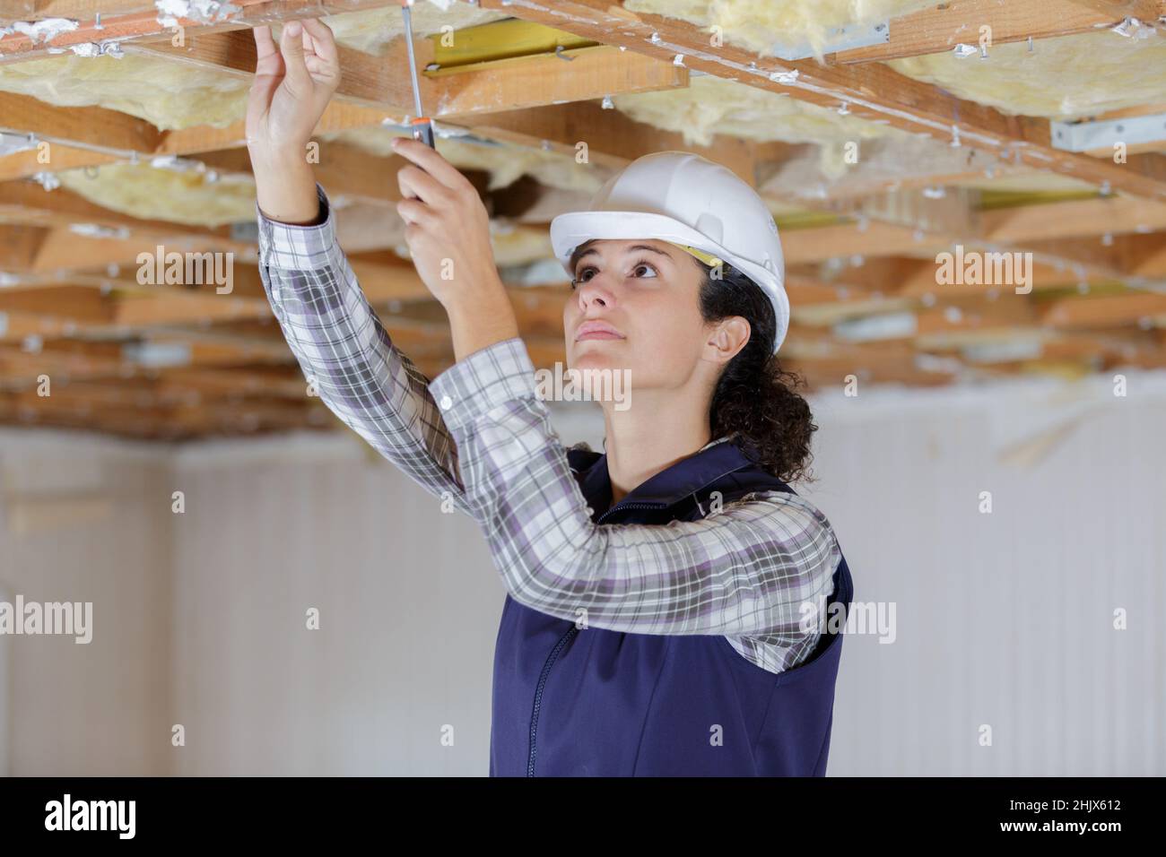 woman in builder hardhat and uniform installing suspended ceiling Stock ...