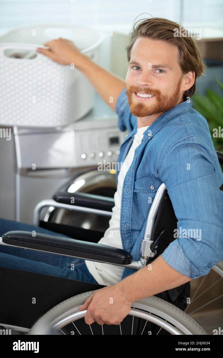 young man in wheel-chair doing ironing at home Stock Photo - Alamy