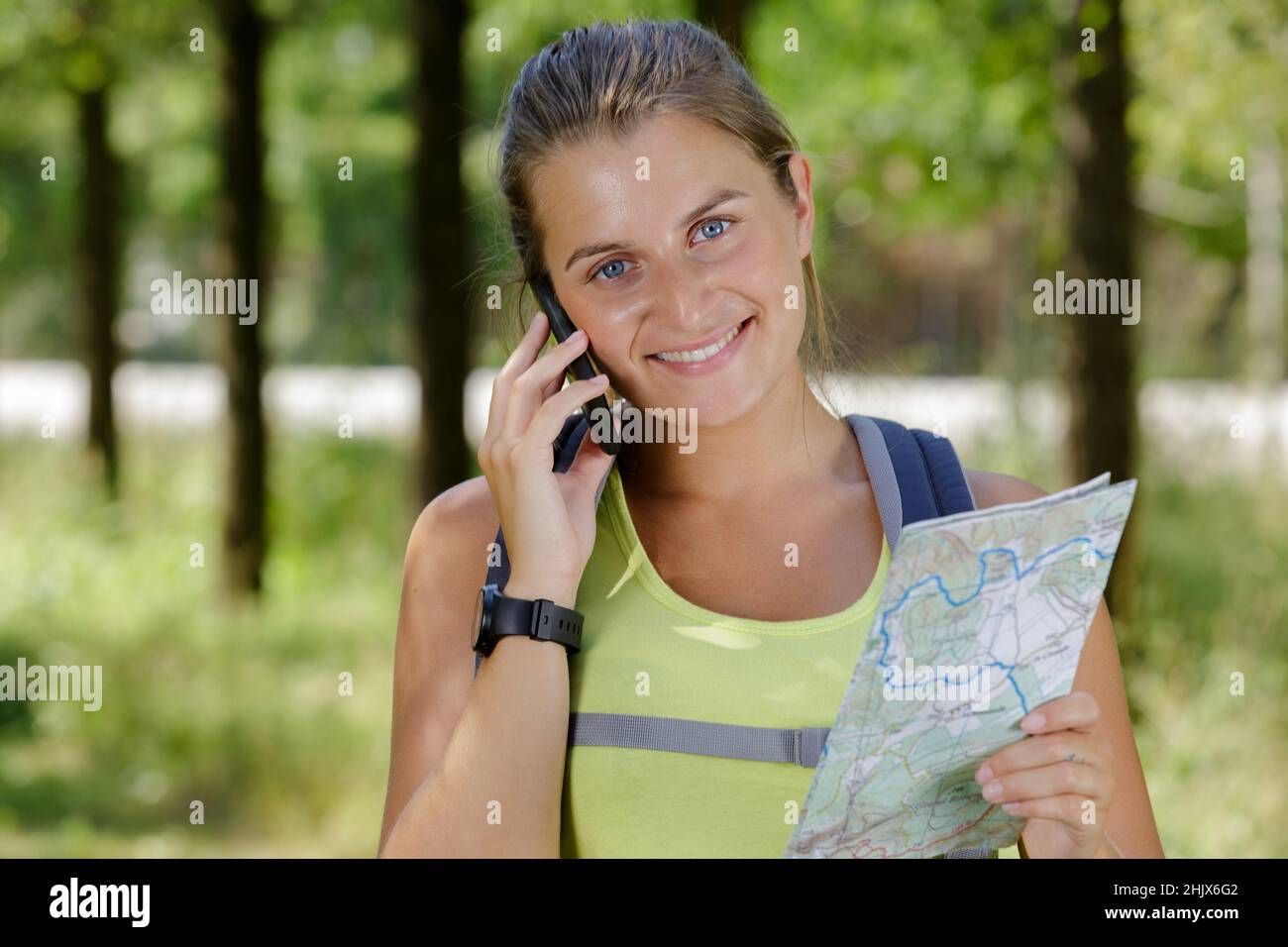 young female hiker holding map while talking to cell Stock Photo - Alamy