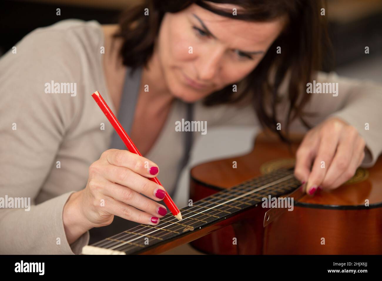 a female luthier holds a pencil Stock Photo - Alamy