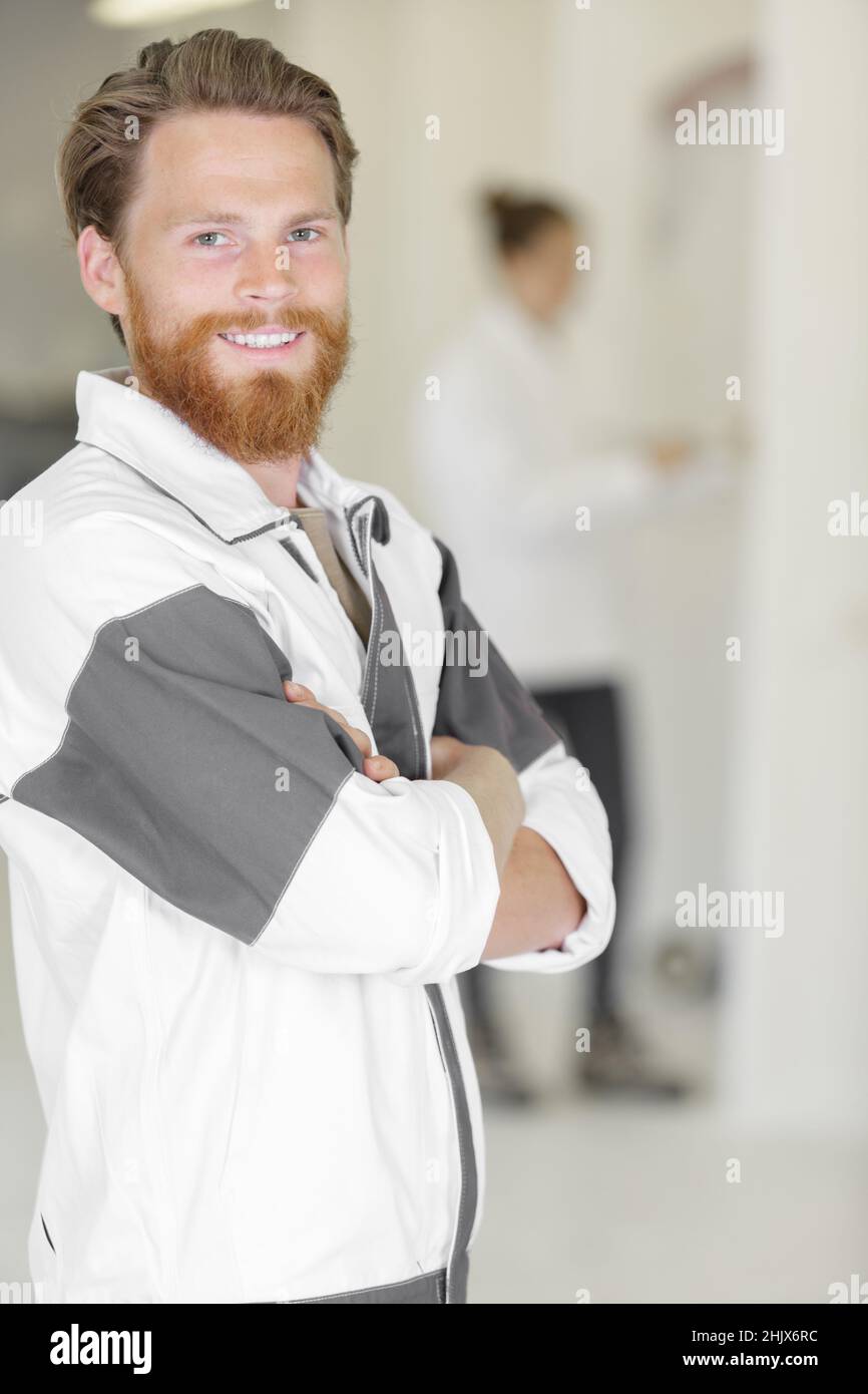 confident smiling painter with white overalls posing with arms crossed ...