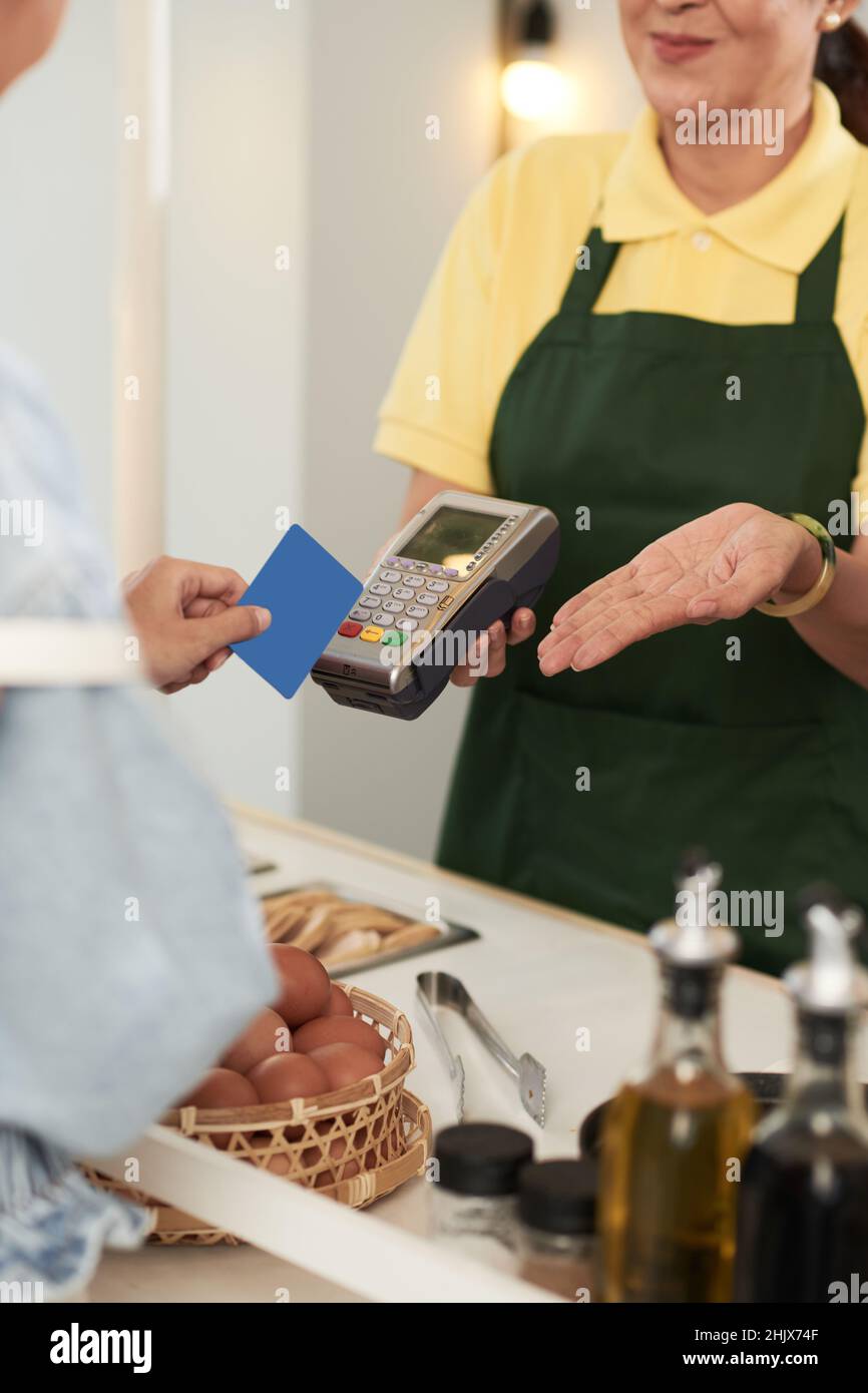 Mature food cart vendor giving credit card reader to customer paying ...