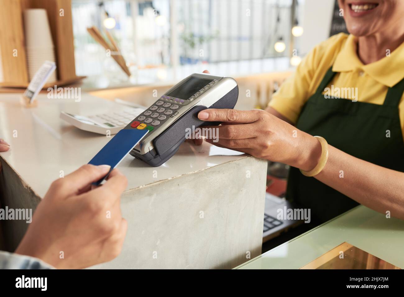 Closeup image of smiling cafe worker accepting payment and giving card ...