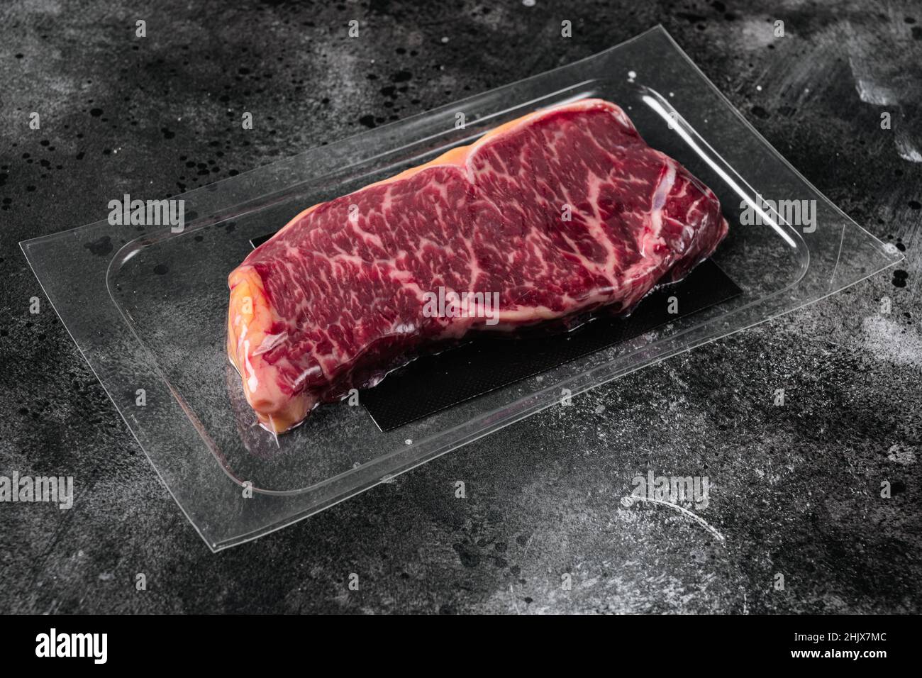 Vacuum packed beef set, on black dark stone table background, with copy ...