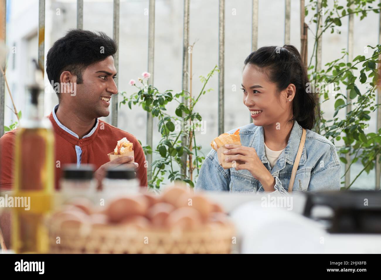 Smiling young boyfriend and girlfriend looking at each other when ...