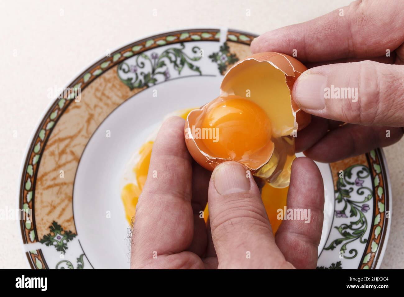 Breaking the egg into the bowl. Cooking time Stock Photo - Alamy