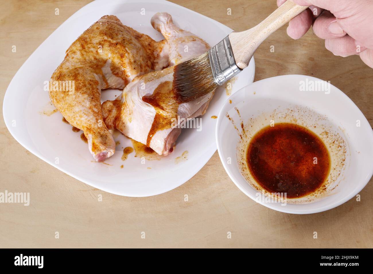 Lubrication of chicken meat with herb marinade. Cooking time Stock ...