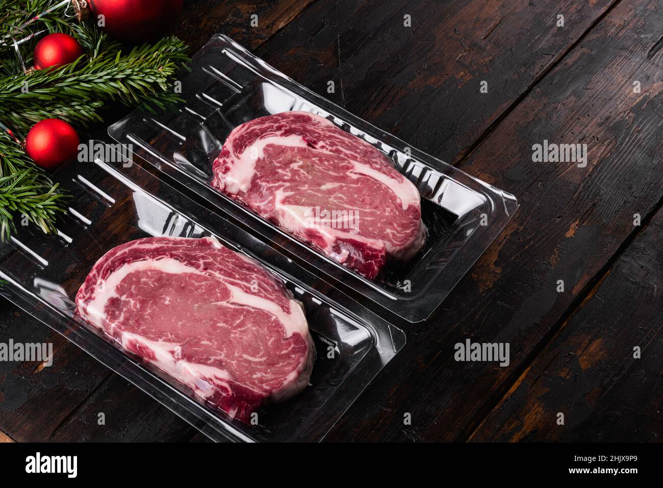 Rib eye steak pack with a Christmas tree set, on old dark wooden table ...