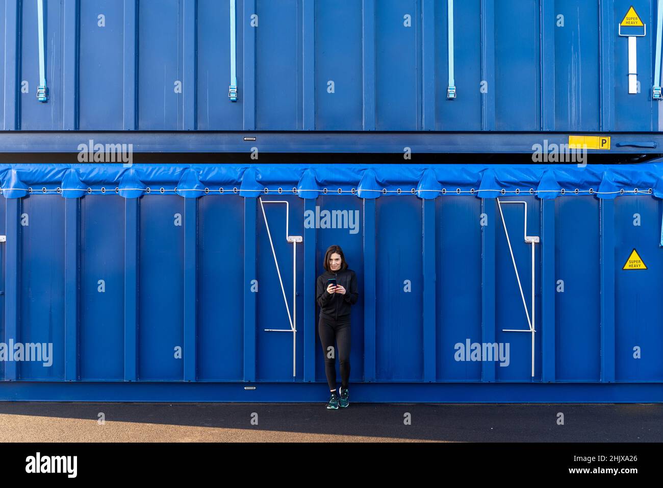young adult female runner is using smartphone among the shipping ...