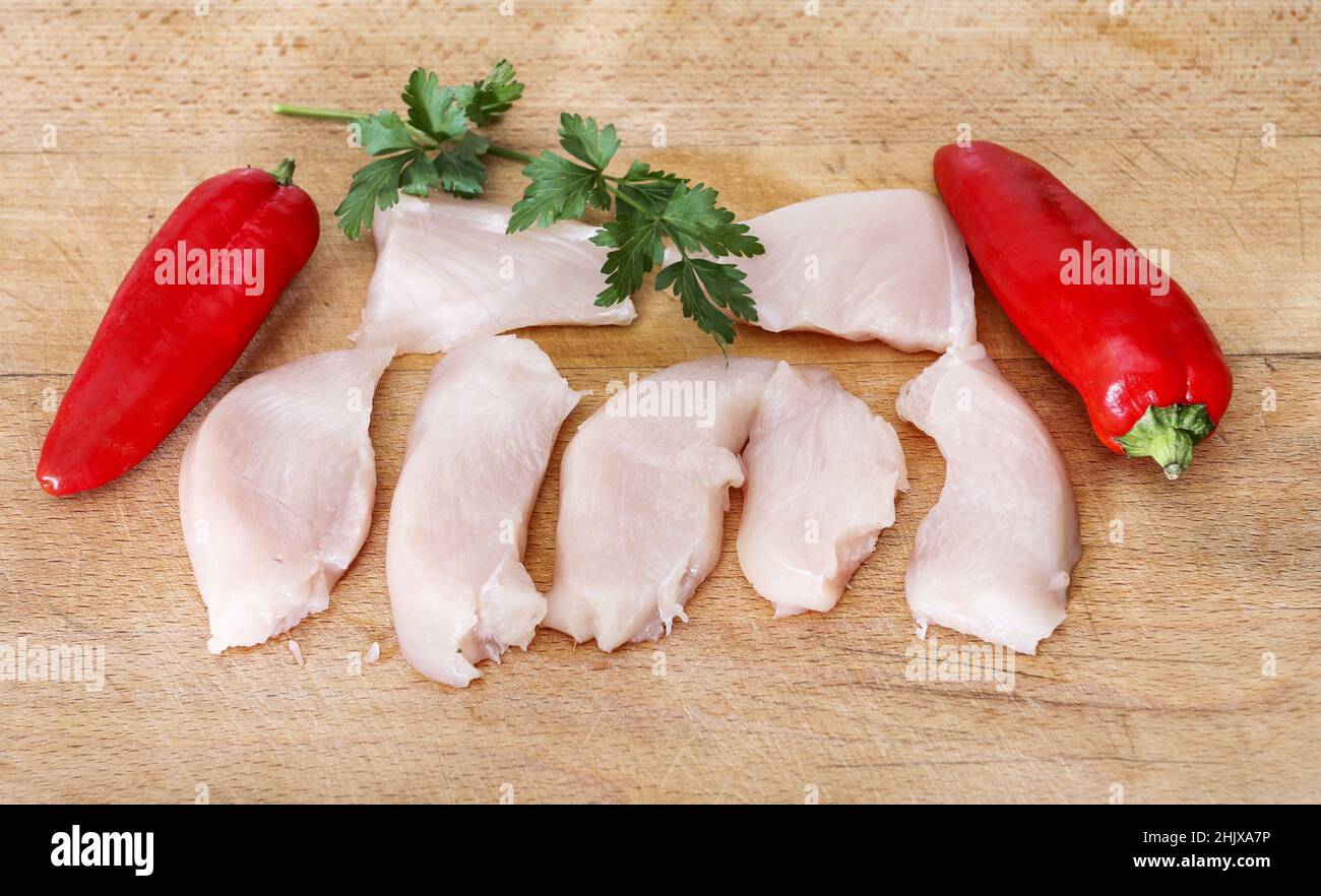Sliced chicken fillet and red pepper on wooden board. Cooking time ...