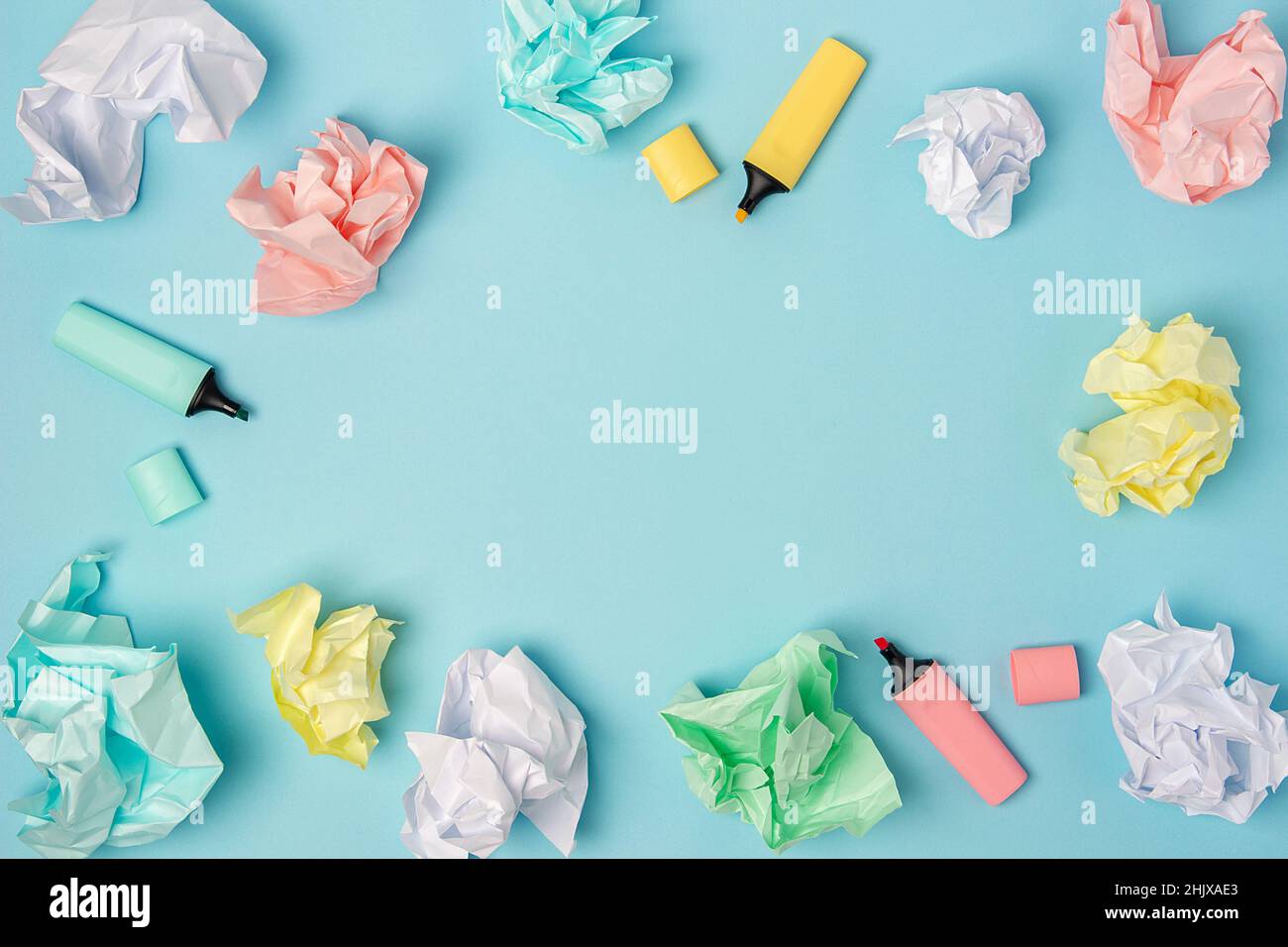 Colored crumpled paper balls and stationery on blue background ...