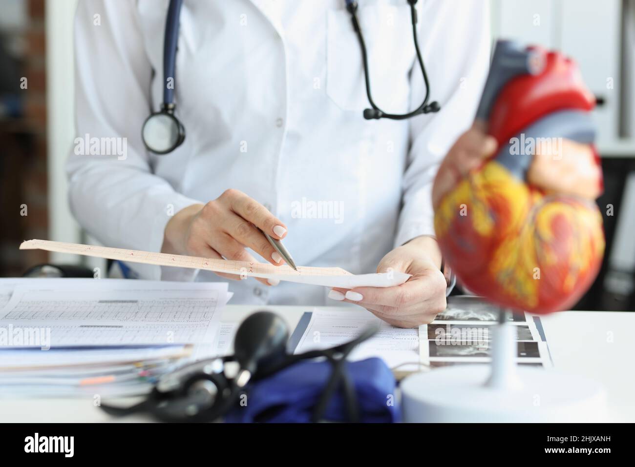 Doctor cardiologist examining cardiogram against background of ...