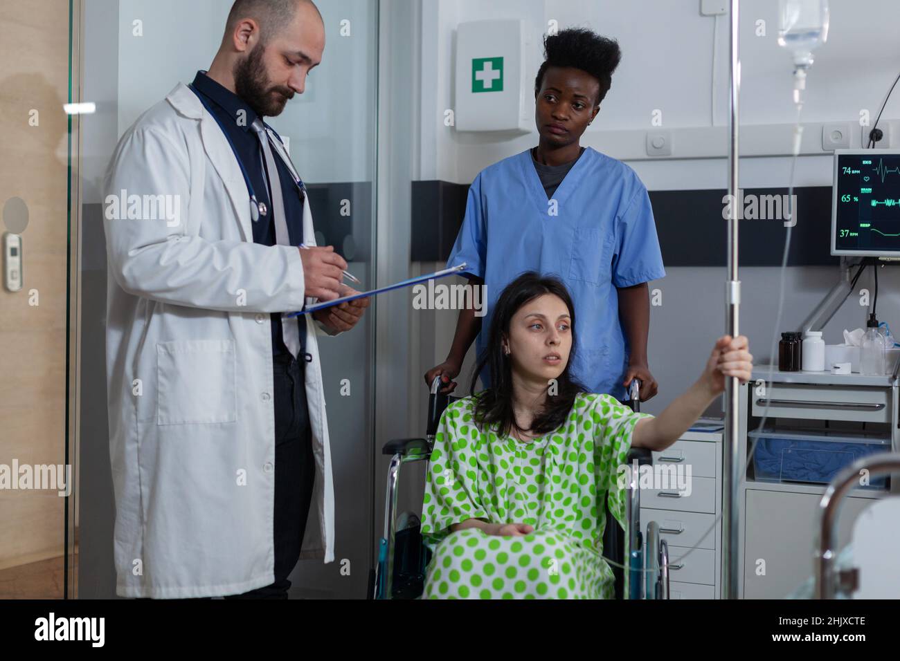Nurse moving to treatment room woman with illness sitting in wheelchair ...