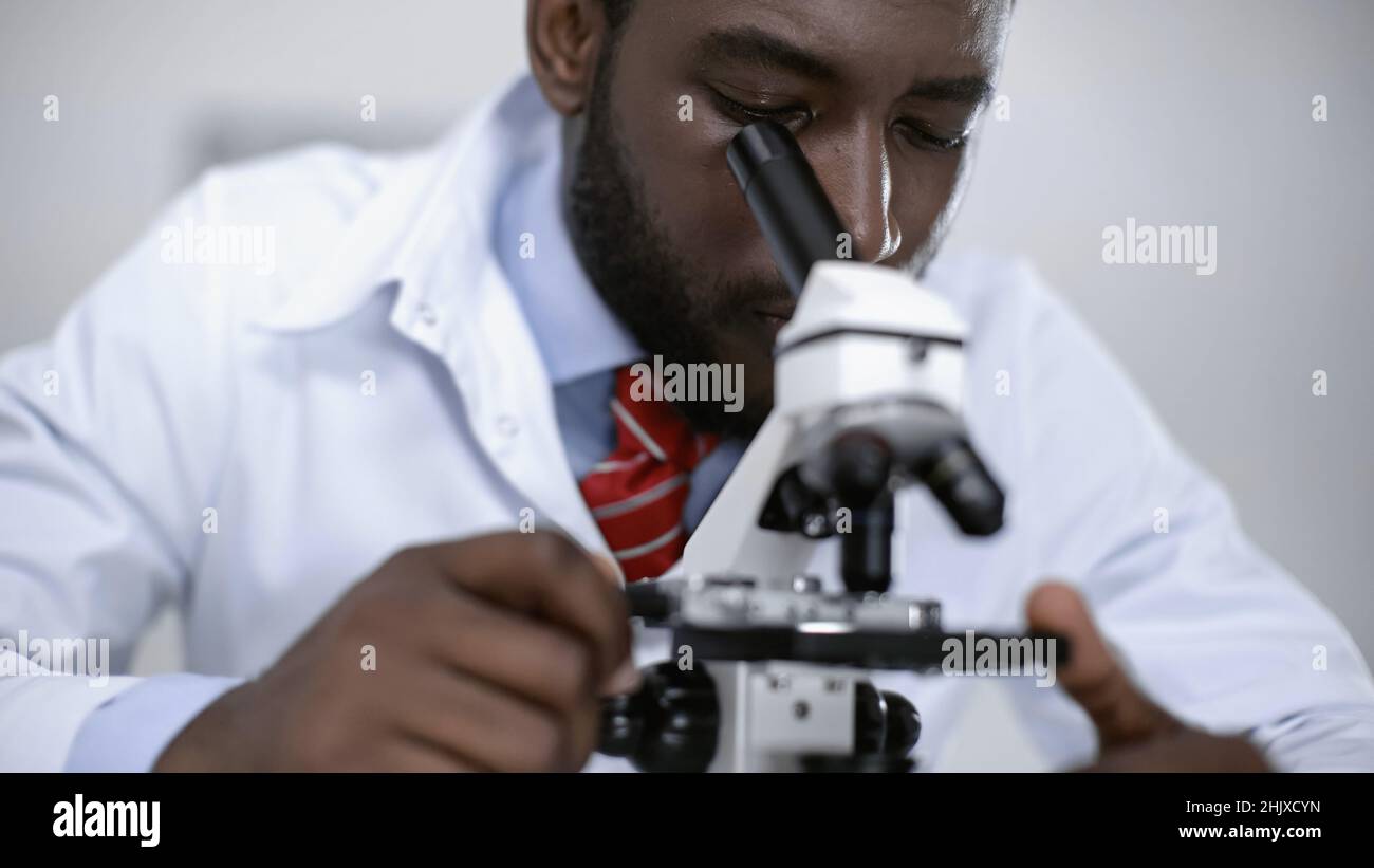 Black man looking through microscope hi-res stock photography and ...