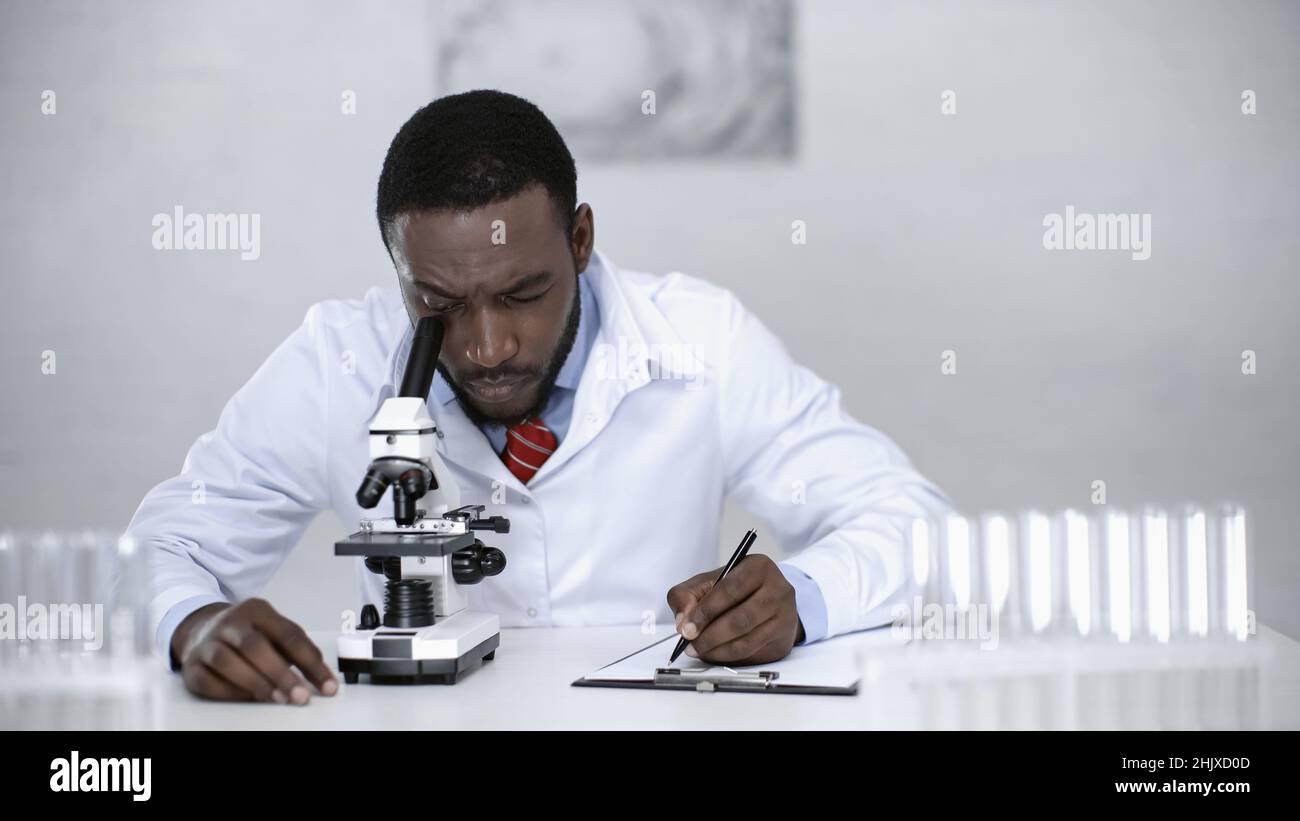 Black man looking through microscope hi-res stock photography and ...