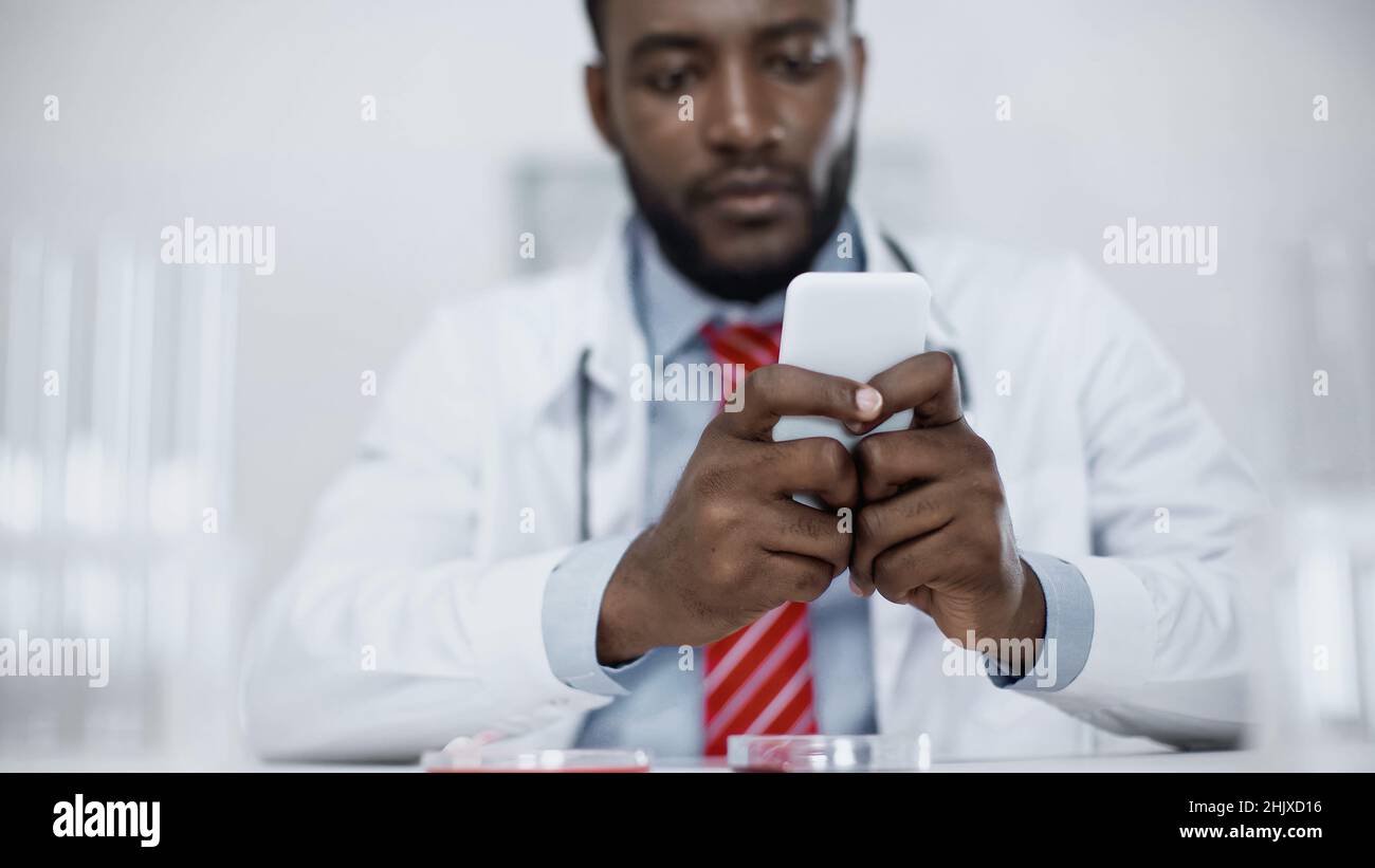 blurred african american doctor messaging on smartphone Stock Photo - Alamy