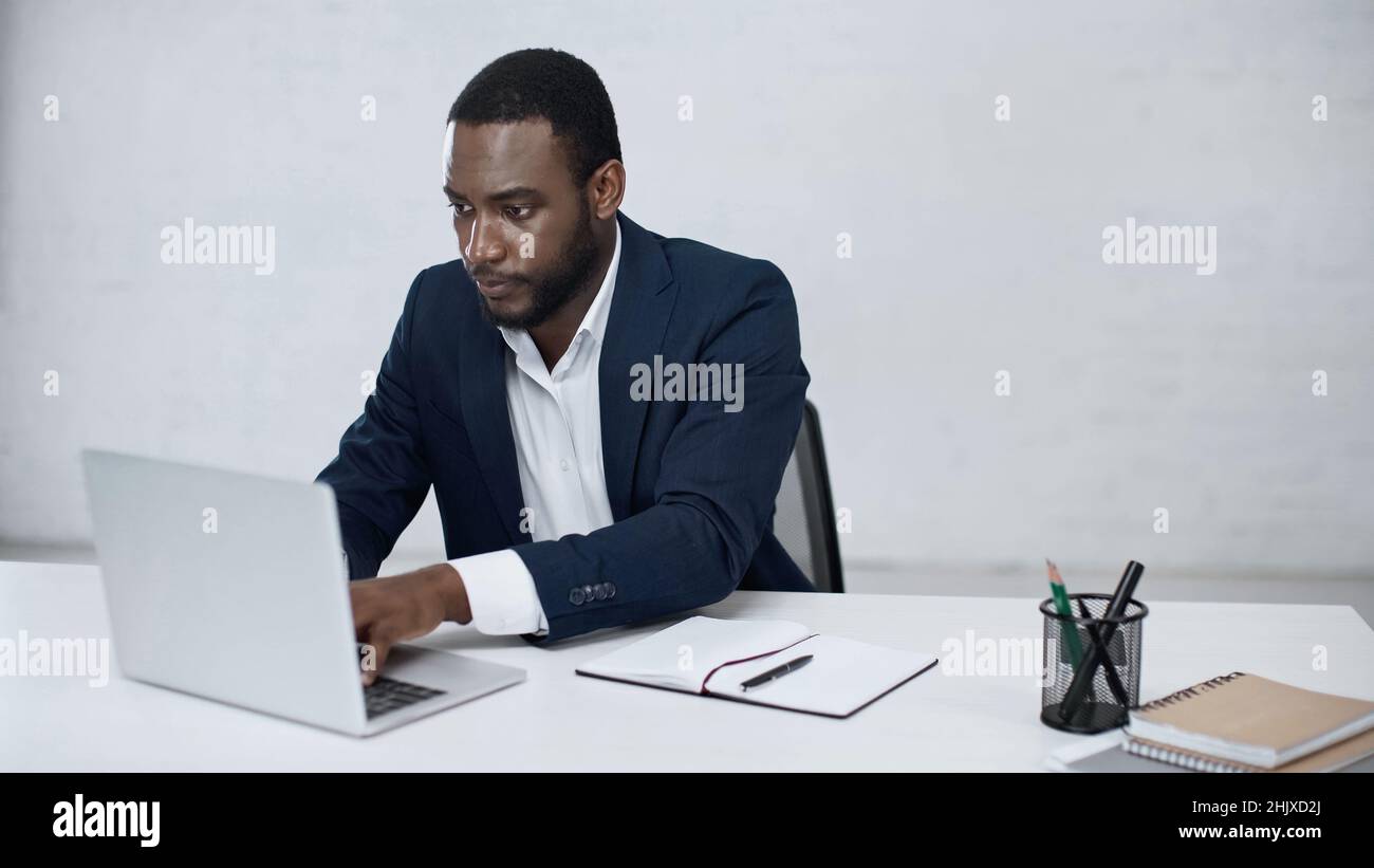 serious african american businessman typing on laptop on grey Stock ...