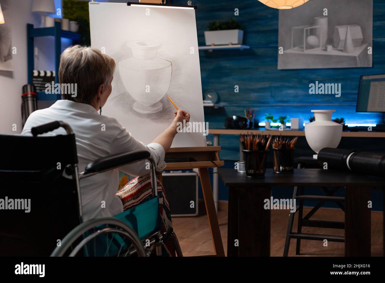 Focused retired art teacher using wheelchair doing creative artwork in ...
