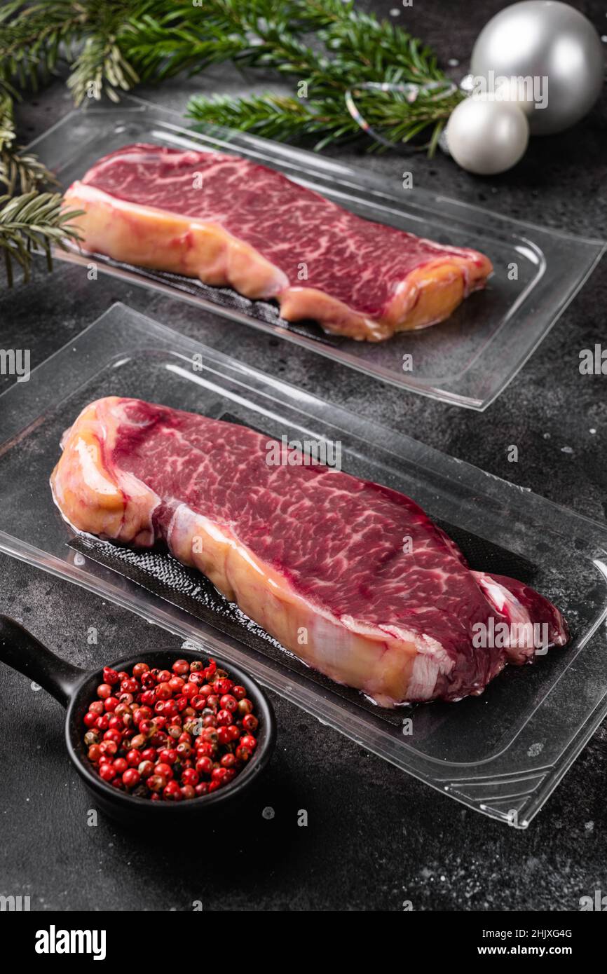 Vacuum packed New-York steak with a Christmas tree set, on black dark ...
